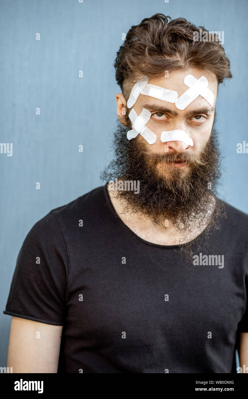 Close-up portrait of an injured man with medical patches on his face on ...