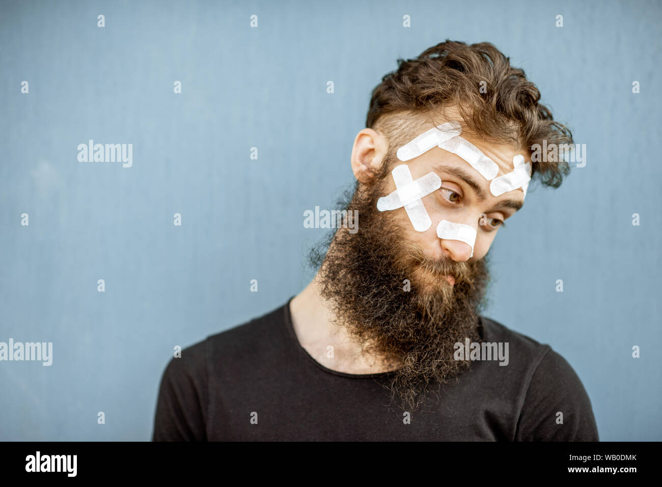 Close-up portrait of an injured man with medical patches on his face on ...