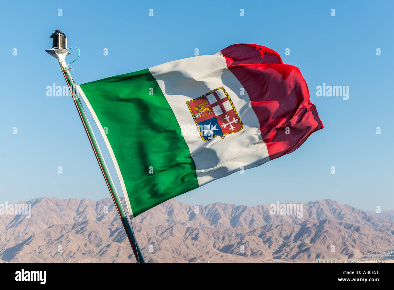 Nautical flag of Italy over a blue sky and mountains background on a ...