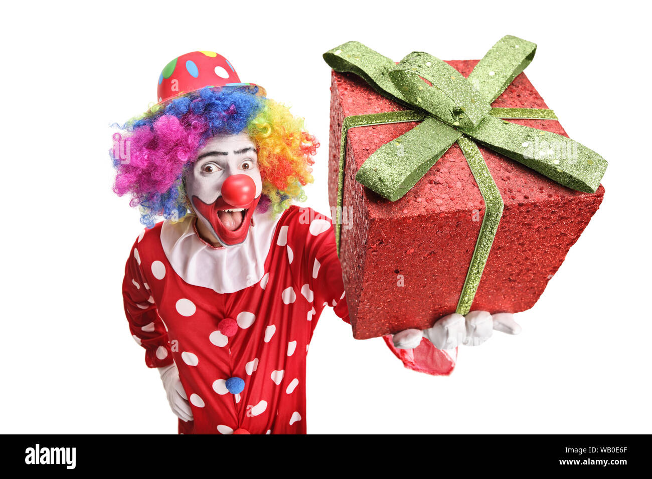 Excited funny clown holding a sparkly red gift box in front of the ...