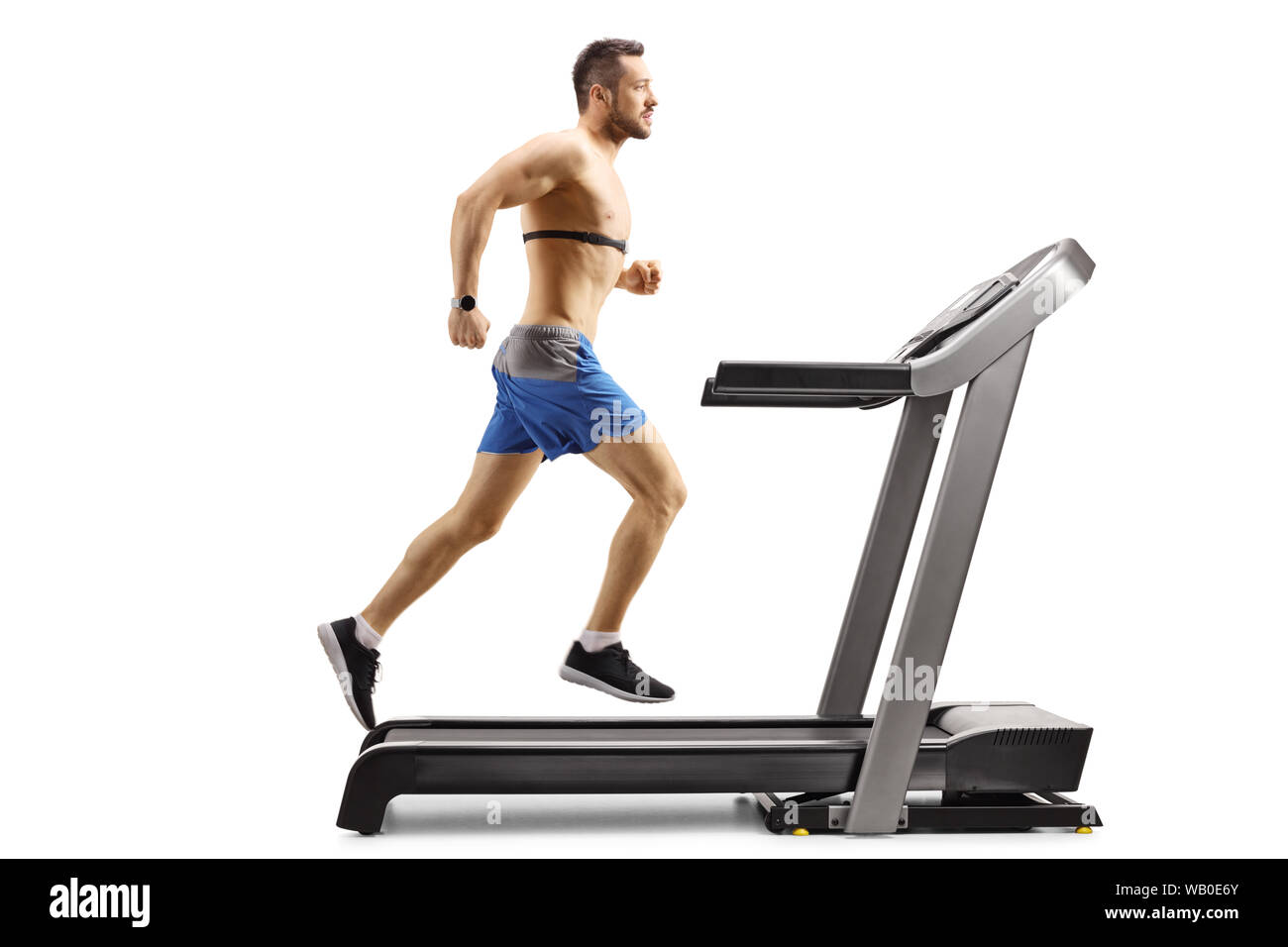 Full length profile shot of a young muscular man running on a treadmill ...