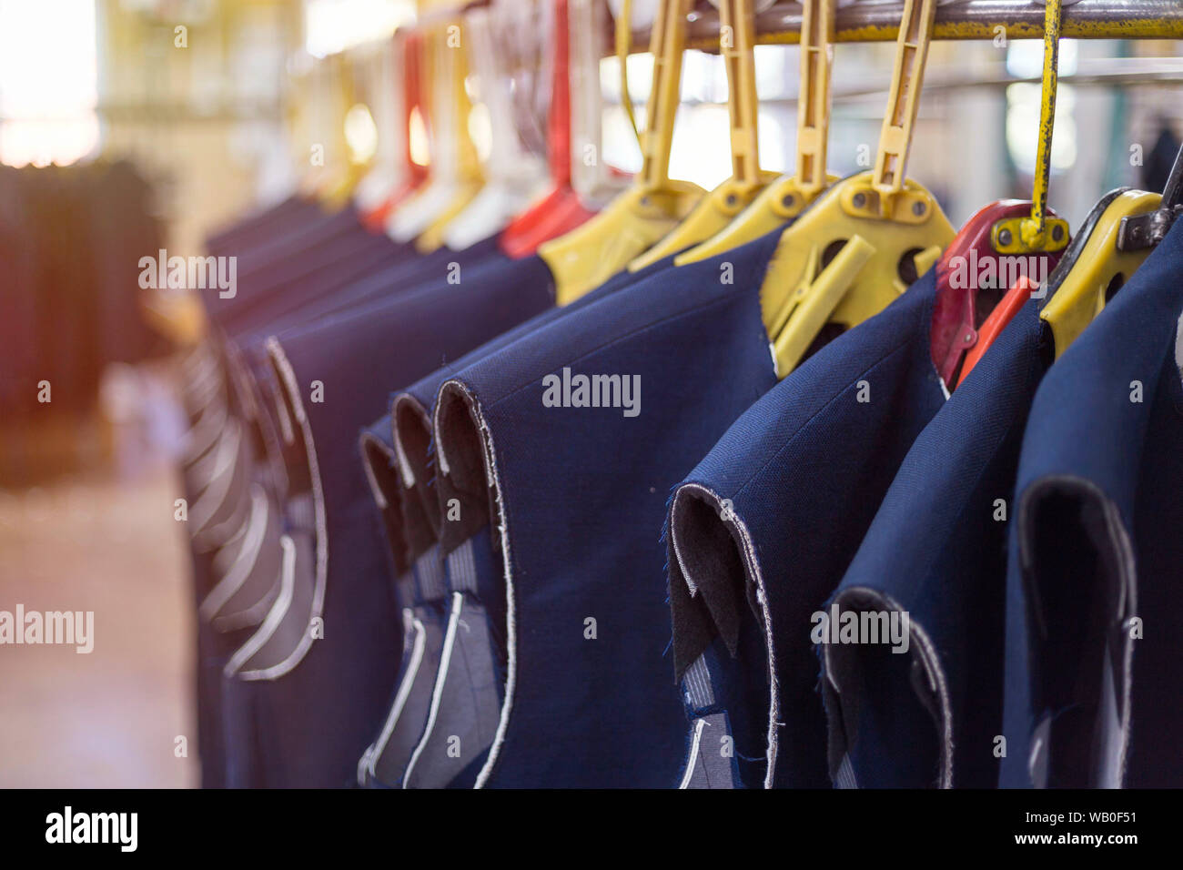 Unfinished suit jackets hanging on assembly line in European garment ...