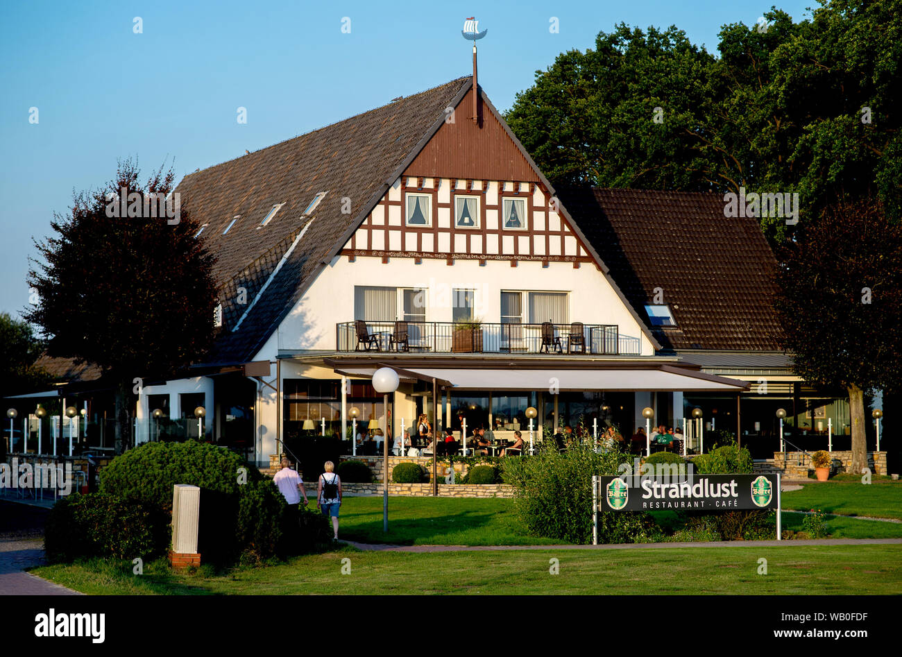 Lembruch, Germany. 22nd Aug, 2019. Guests sit in the evening sun on the ...