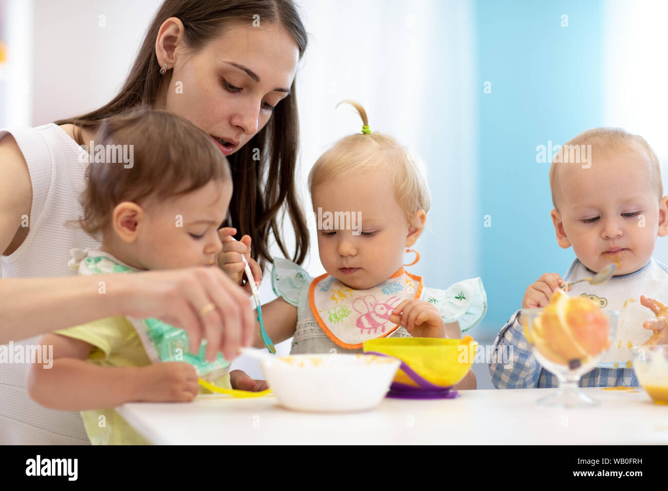 Group of nursery babies having lunch together with kindergartener. Cute ...