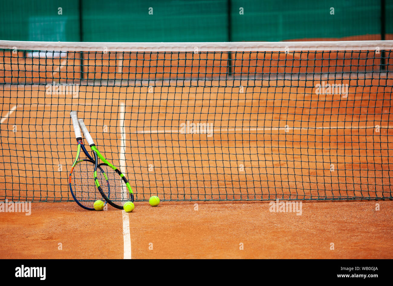 Two tennis rackets and balls leaned against the net Stock Photo - Alamy