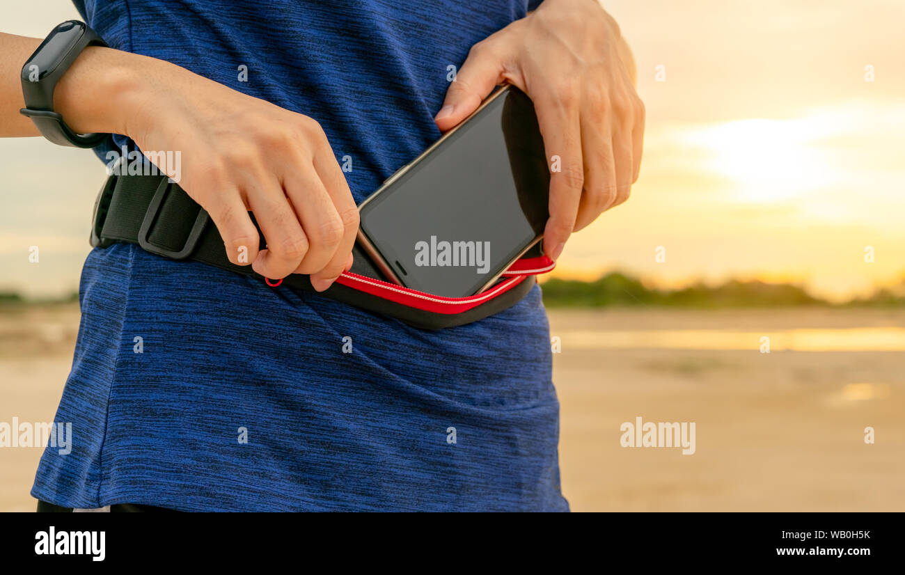 Young Asian woman keep smartphone in waist bag before running cardio ...
