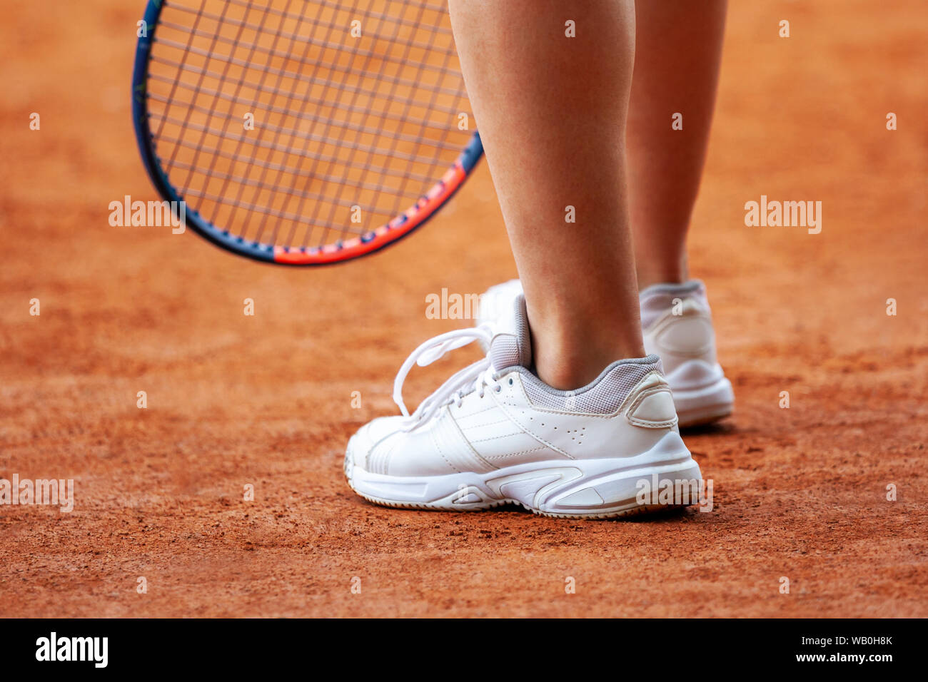 Female Tennis Player Legs In Tennis Shoes Standing On A Clay Court