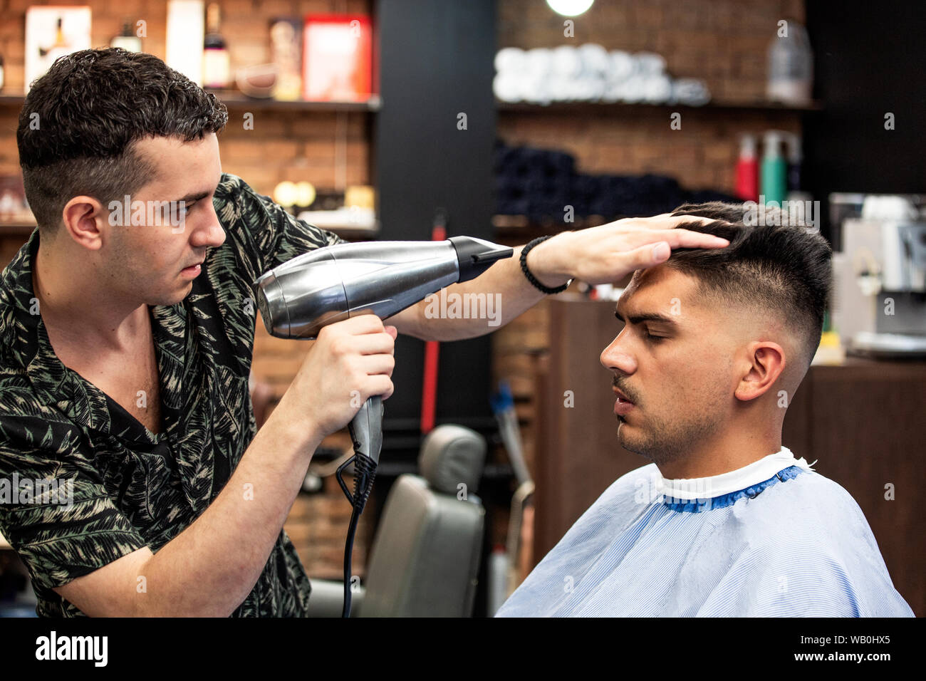 Close-up, master Barber does the hairstyle and styling with dryer ...