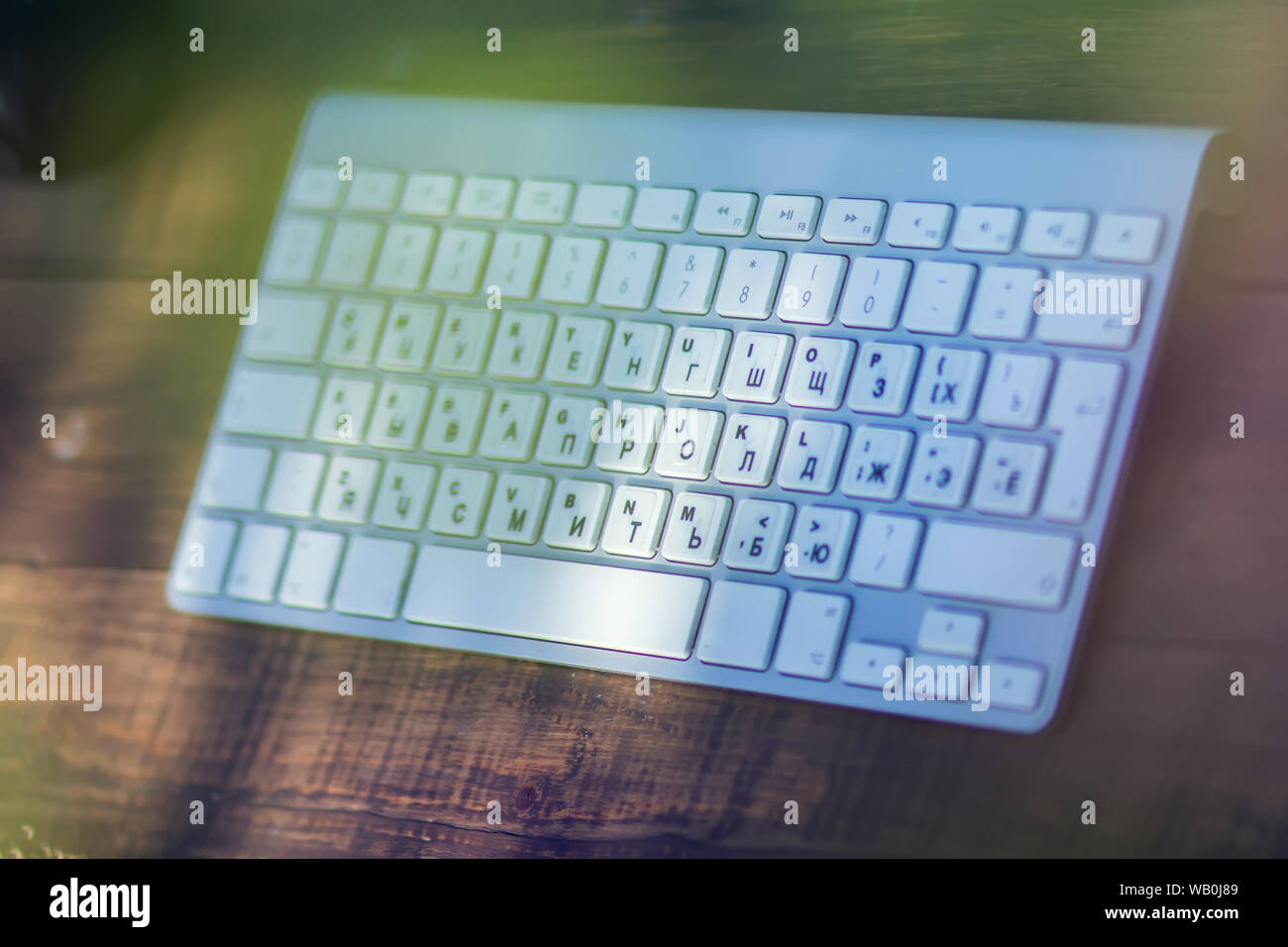 White keyboard on the wooden table outdoor. Technology and office ...