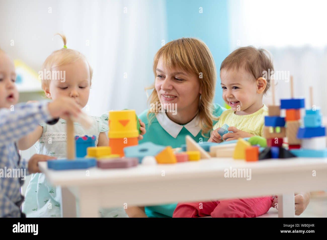 Nursery babies playing with teacher in the classroom Stock Photo - Alamy
