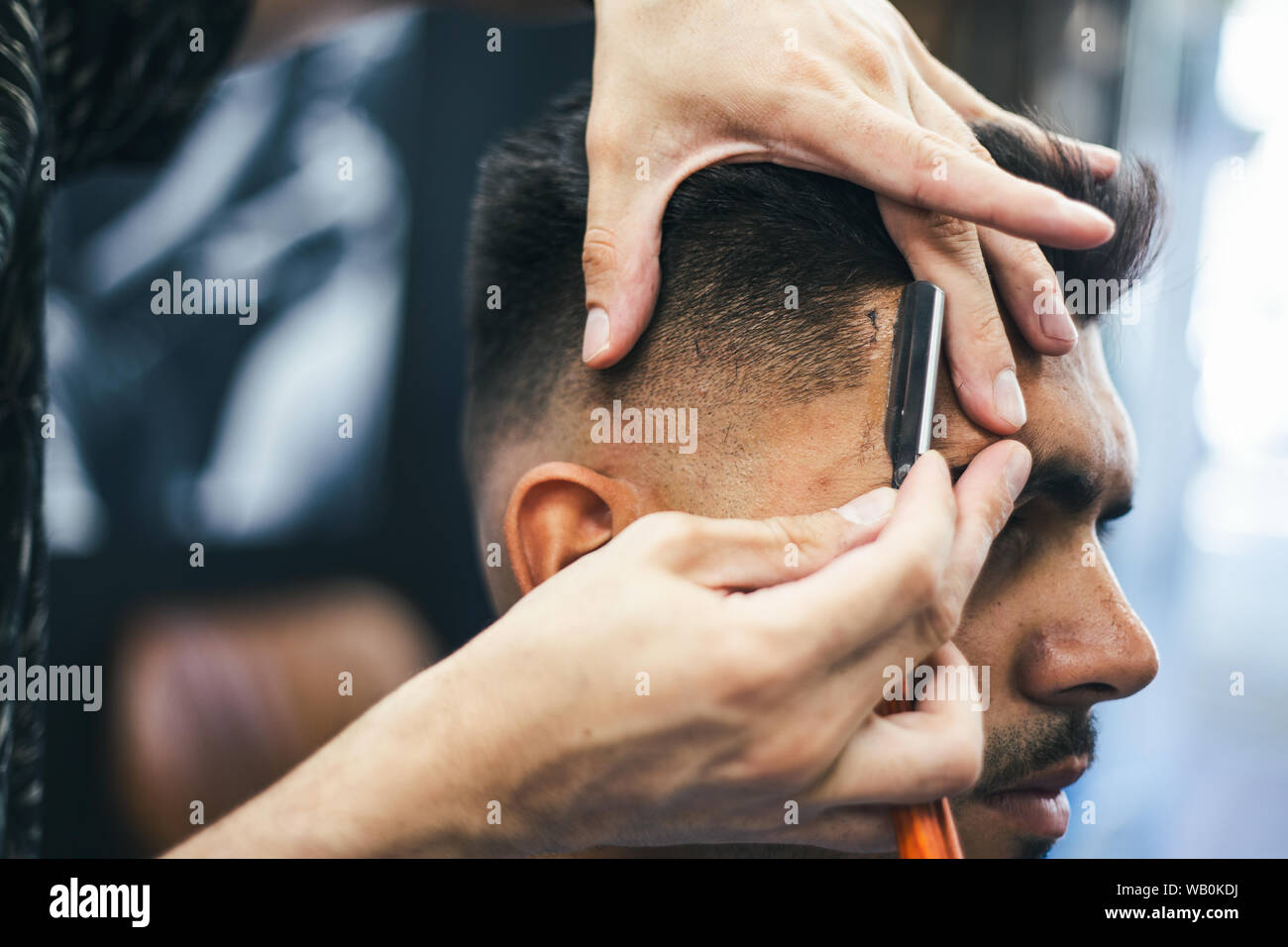 Razor in hands of professional barber. Hairdresser shaving man's hair ...