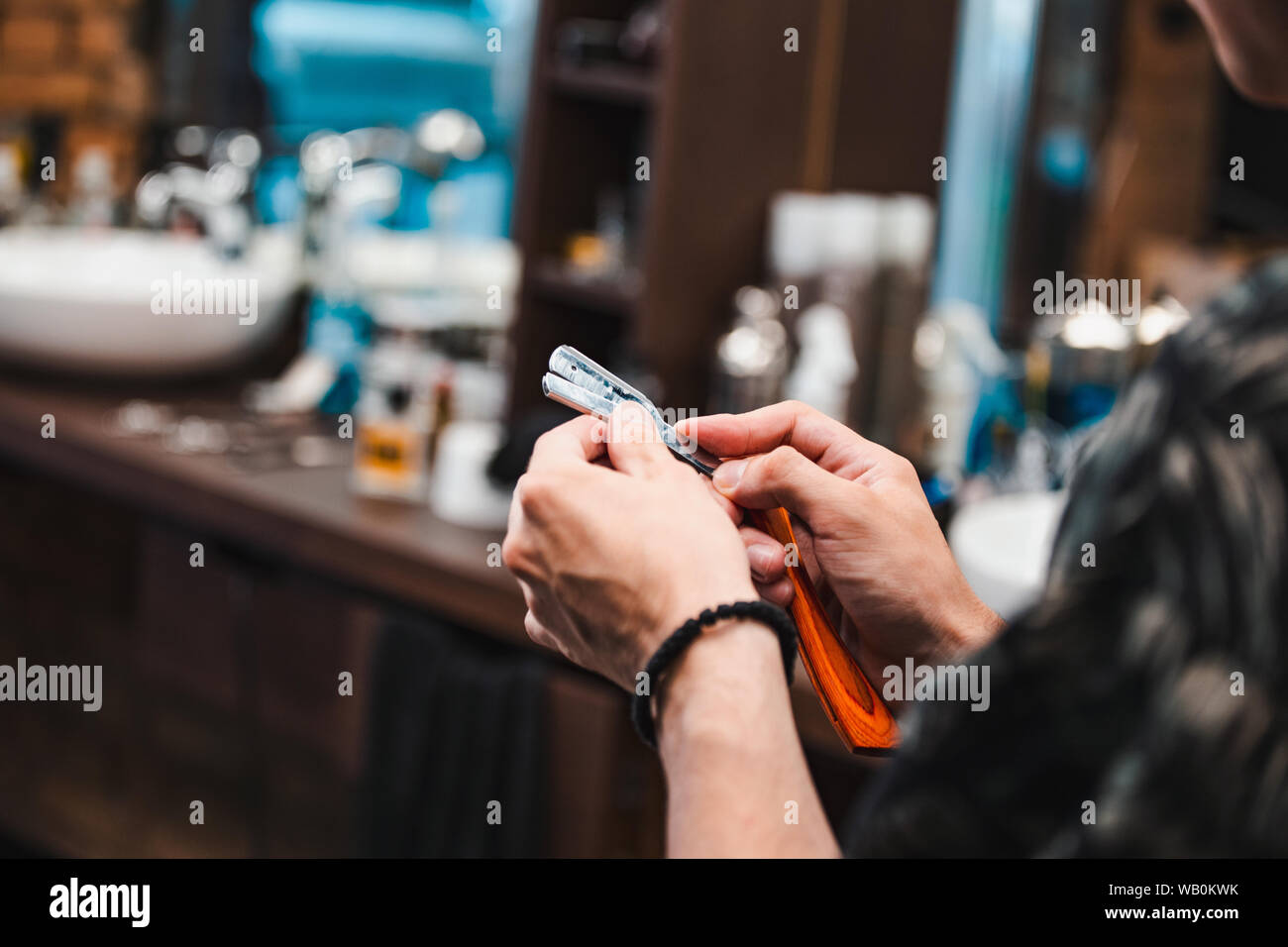 Master disinfecting shaving instrument before use. Young man spray ...