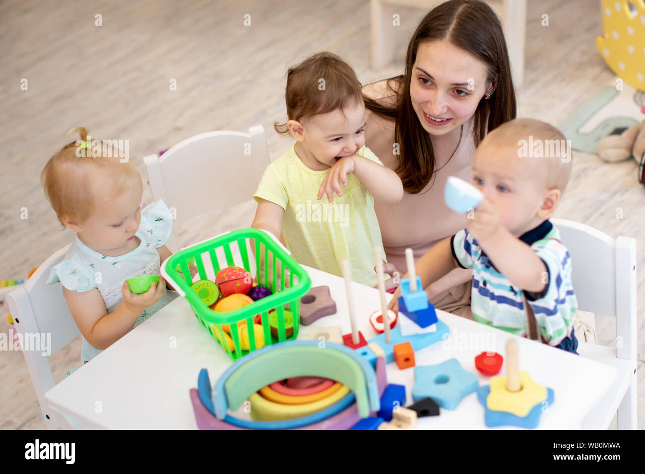 Nursery babies playing with teacher in kindergarten. Top view of kids ...