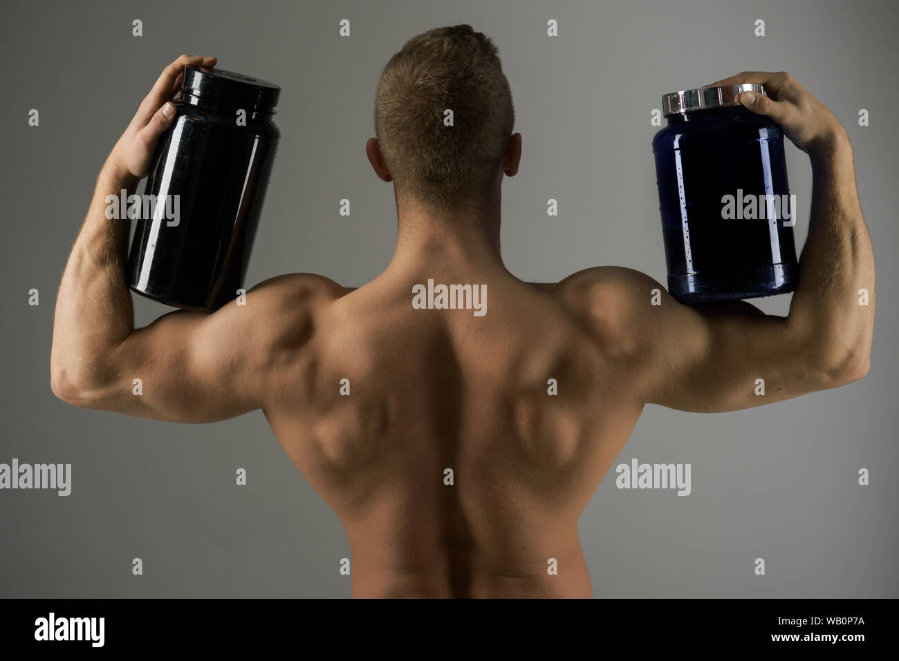 Promoting proper body functioning. Strong man hold supplement bottles ...