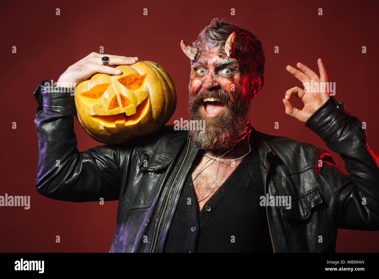 Halloween happy man demon hold pumpkin on brown background. Satan with ...