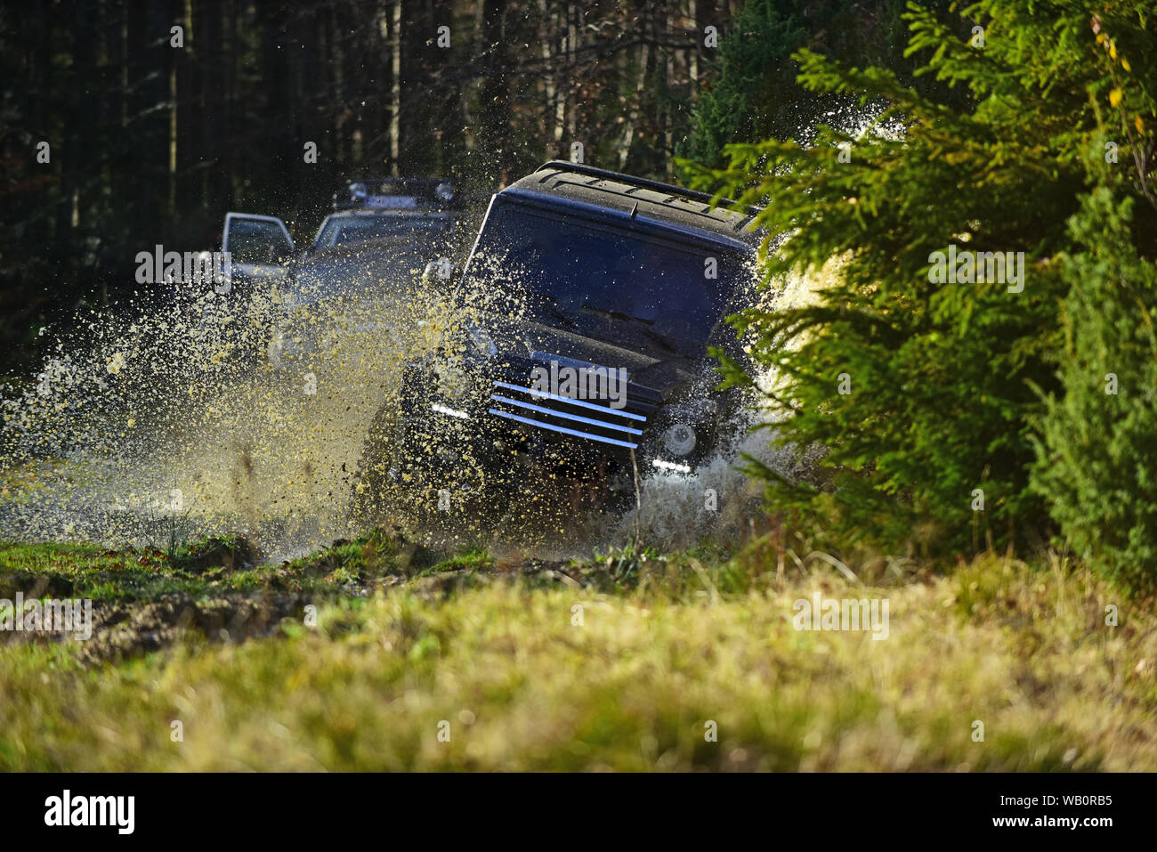 Sport utility vehicle or SUV crossing puddle with splash. Rallying ...