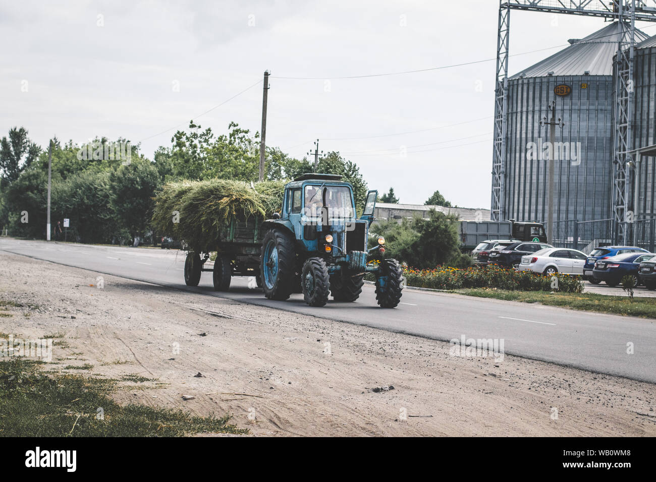 Tractor with hay wagon. Tractor pulling a trailer with hay across a ...
