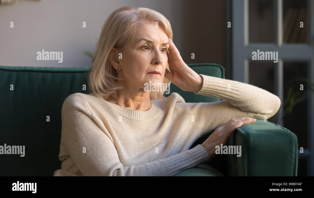 Pensive middle aged lady looking away sit alone at home Stock Photo - Alamy
