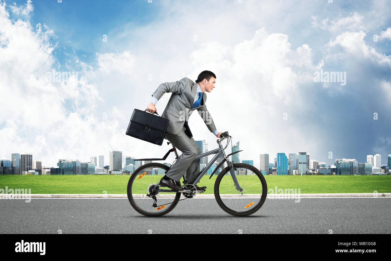 Man riding bicycle on highway at sunny day. Businessman on bike hurry ...
