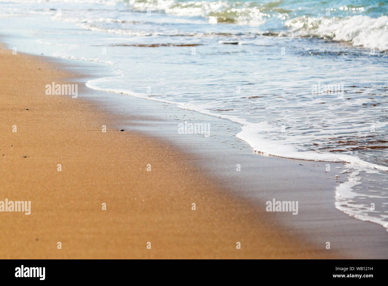 The sandy beach is yellow in color and the waves are rolling in the ...