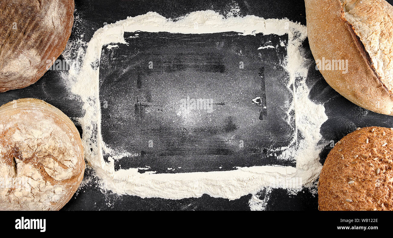 baked various loaves of bread on a black background, empty space in the ...