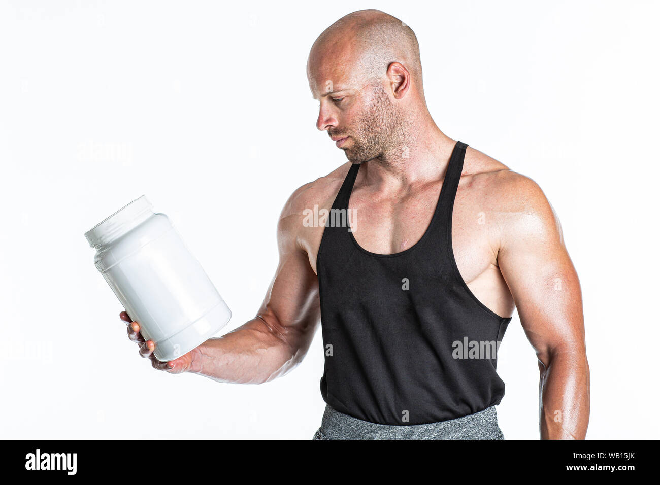 Strong bodybuilder holding a plastic jar with a dry whey protein ...