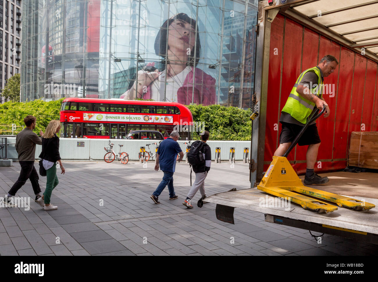 A delivery man manoeuvres a pallet trolley with the head of a model as ...