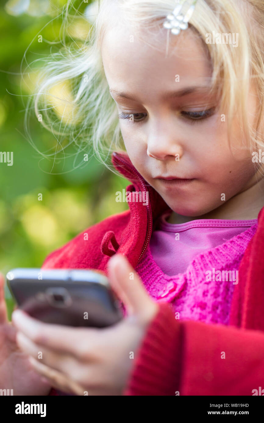 Portrait of little girl using smartphone Stock Photo - Alamy