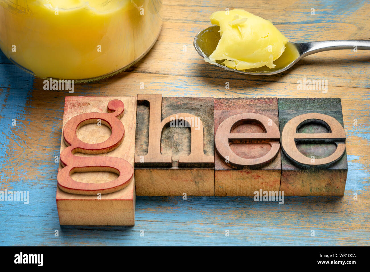 jar and tablespoon of ghee (clarified butter) on grunge wood with a ...