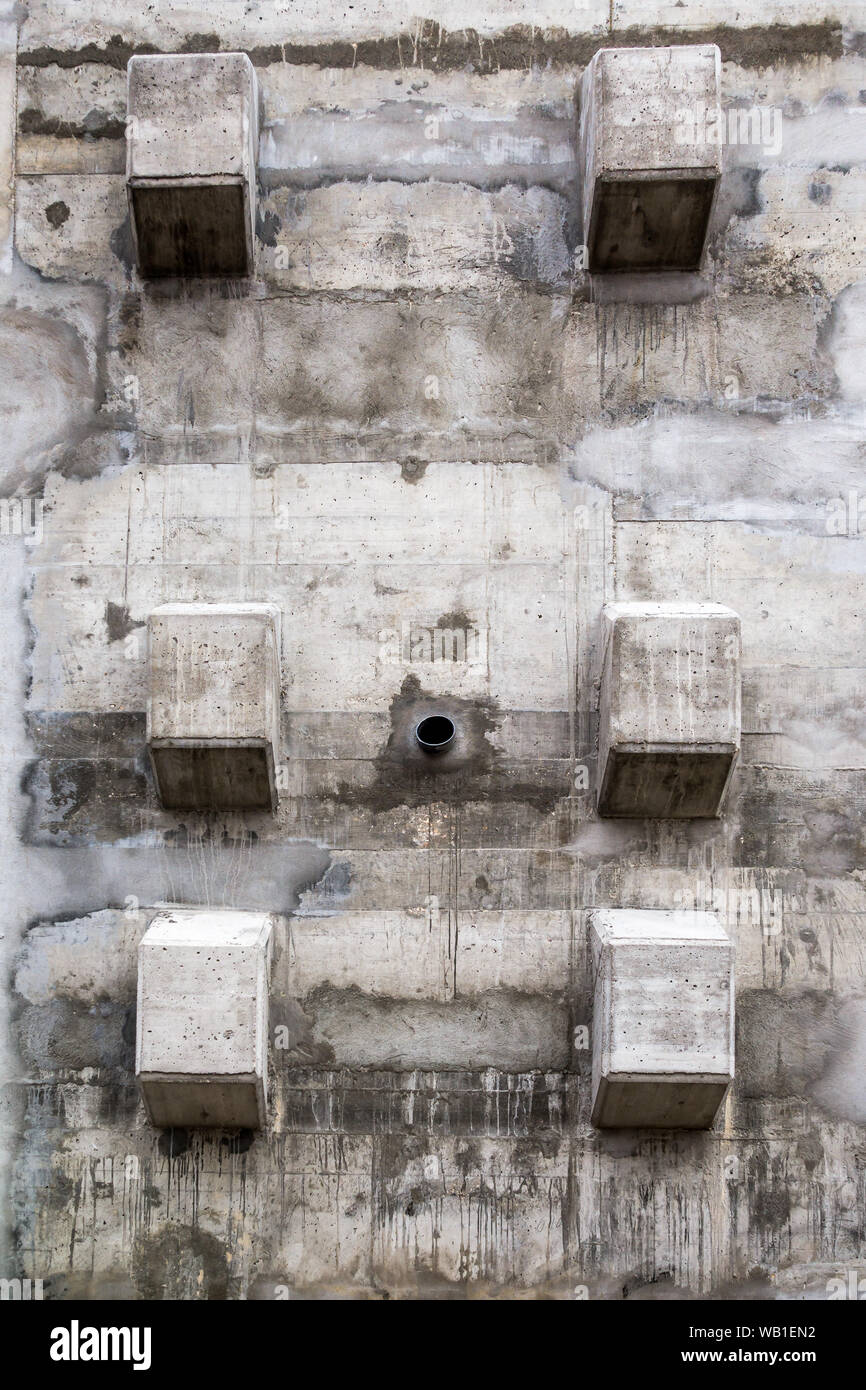 Concrete wall supporting building foundations behind with raw texture ...