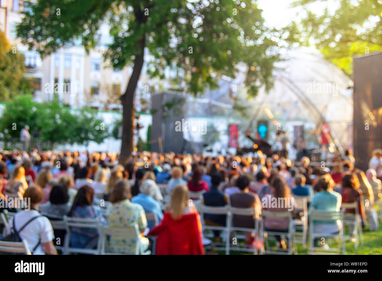 Summer street concert on an open stage with spectators sitting on ...