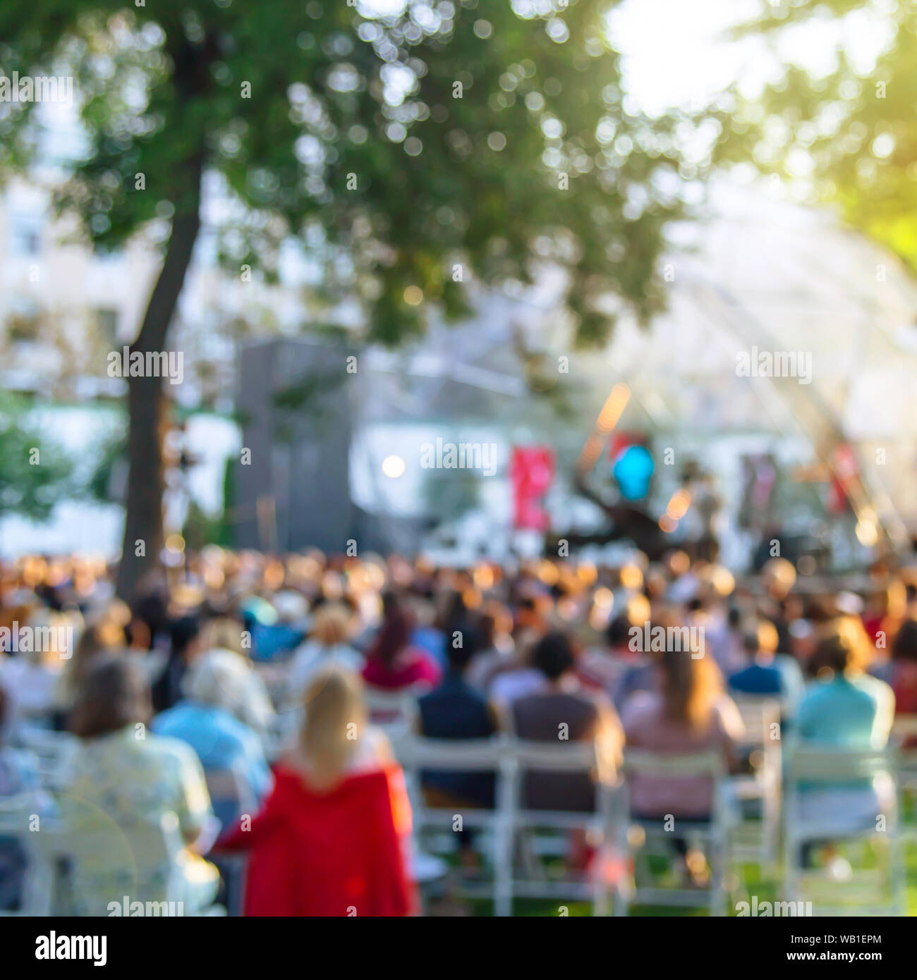 Summer street concert on an open stage with spectators sitting on ...