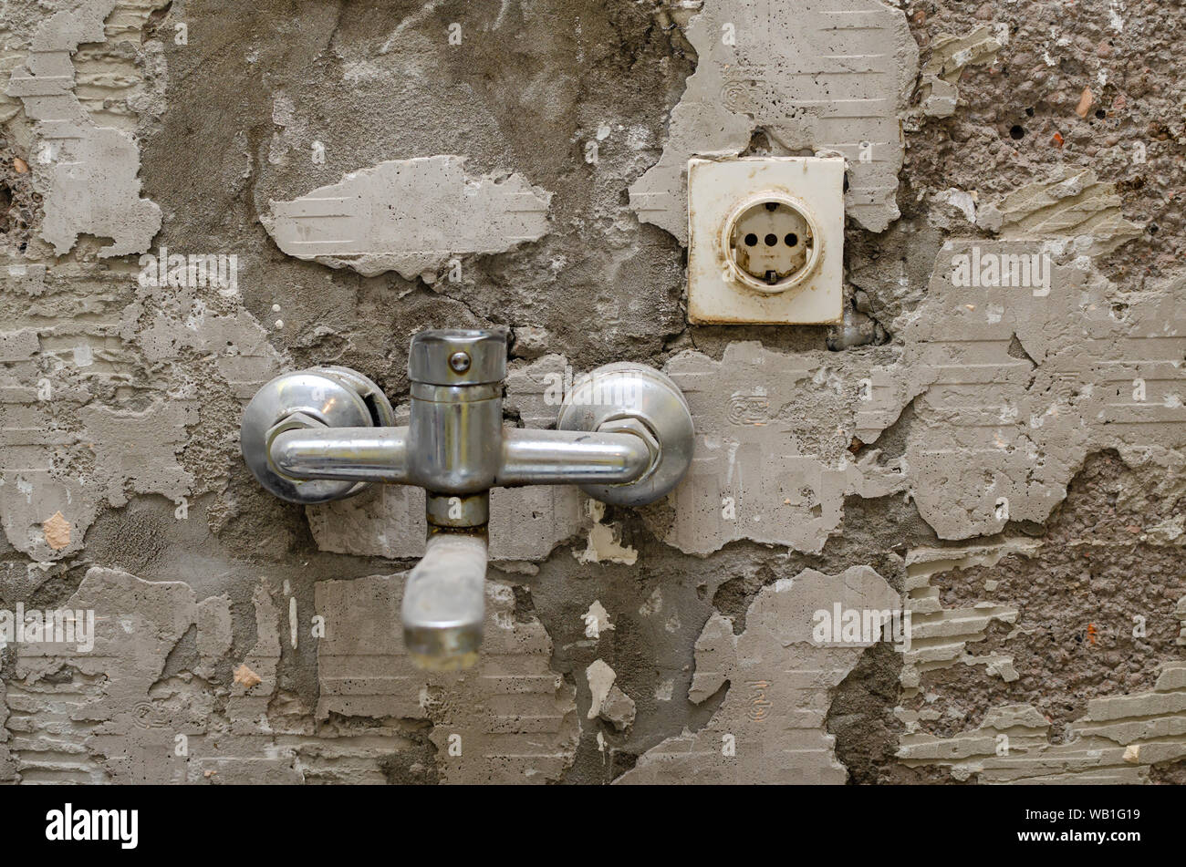 Old kitchen tap and a socket on a scraped wall during reconstruction ...