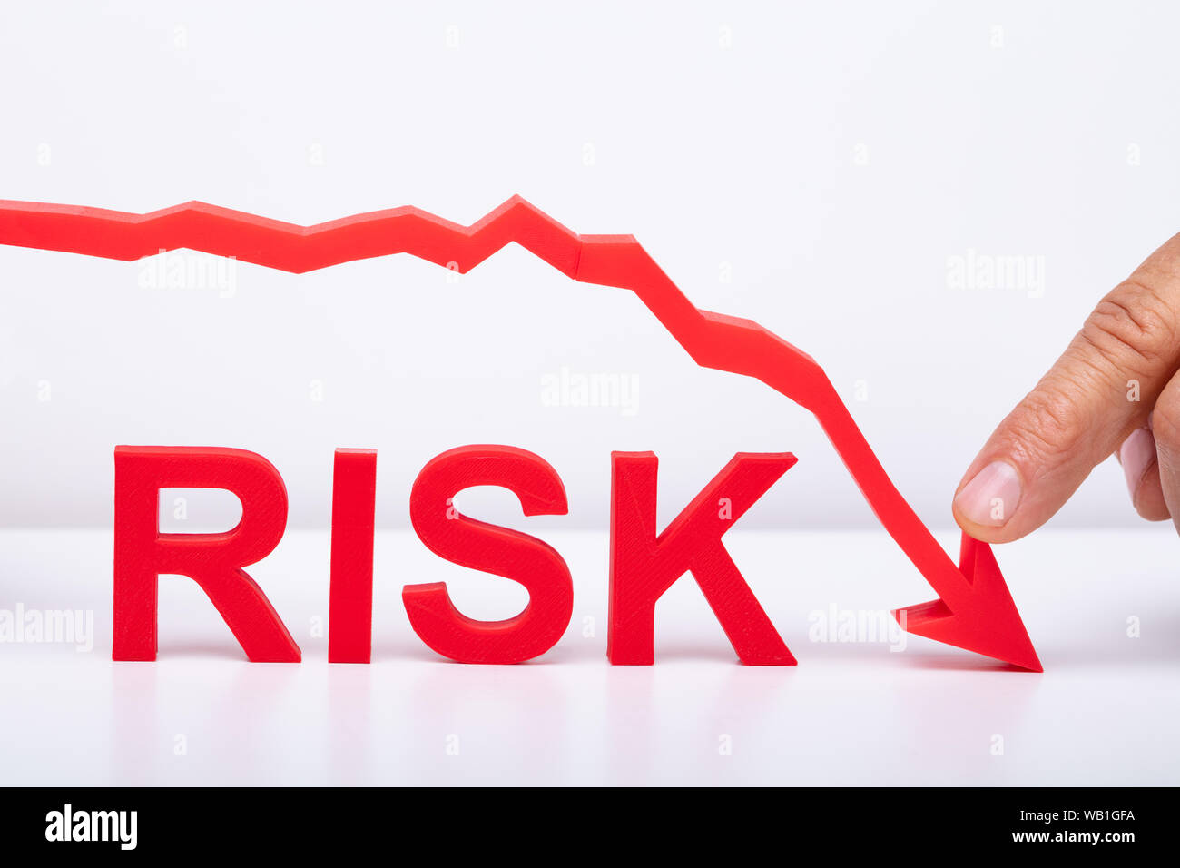 Businessman Pointing Red Diminishing Arrow Over The Risk Text On Desk ...