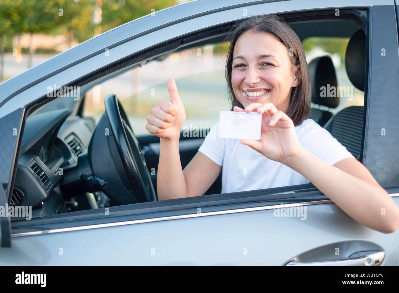 Young woman holding driver license in her car Stock Photo - Alamy