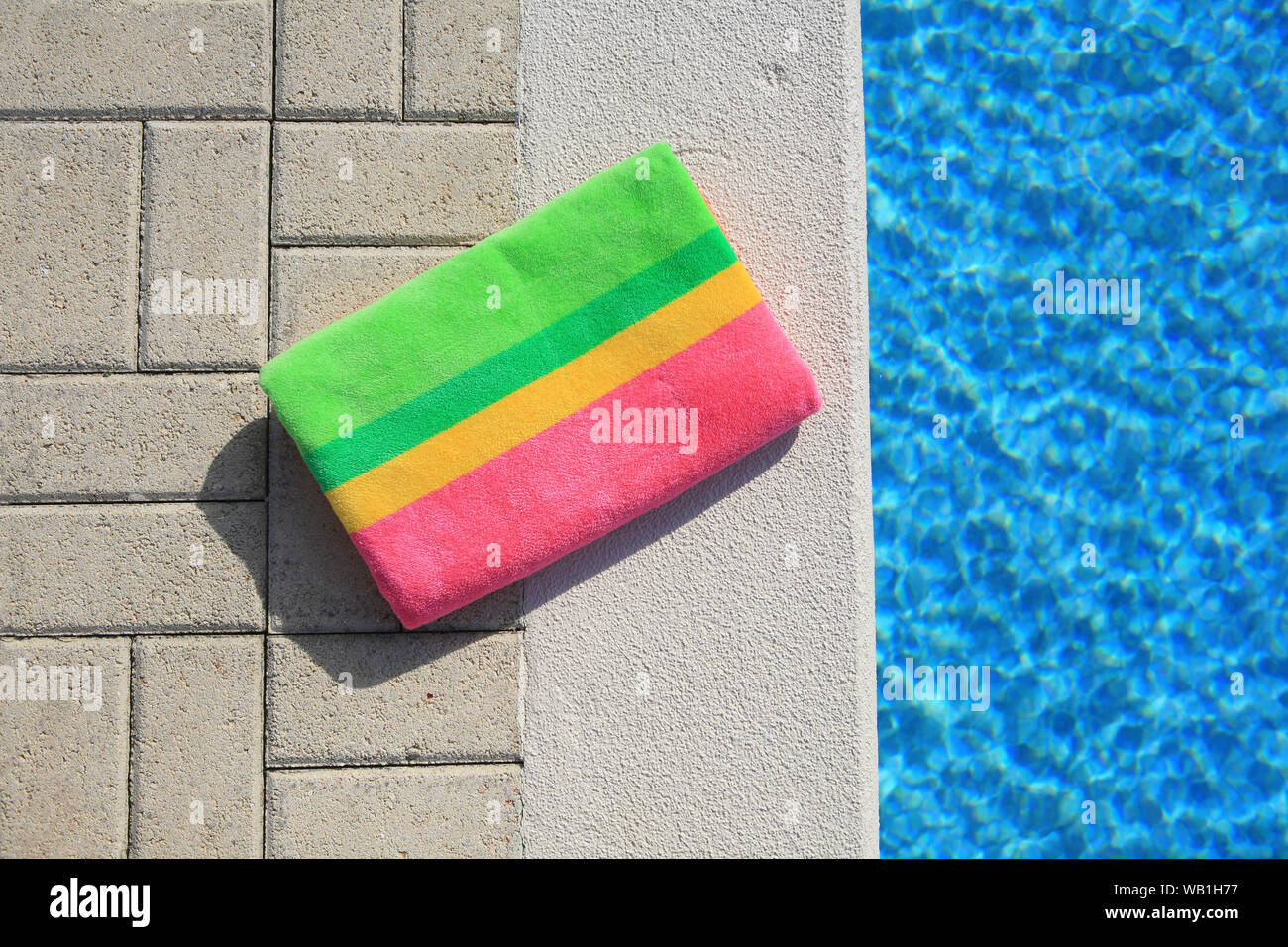 Stripes colored towel at the edge of an outdoor pool Stock Photo - Alamy