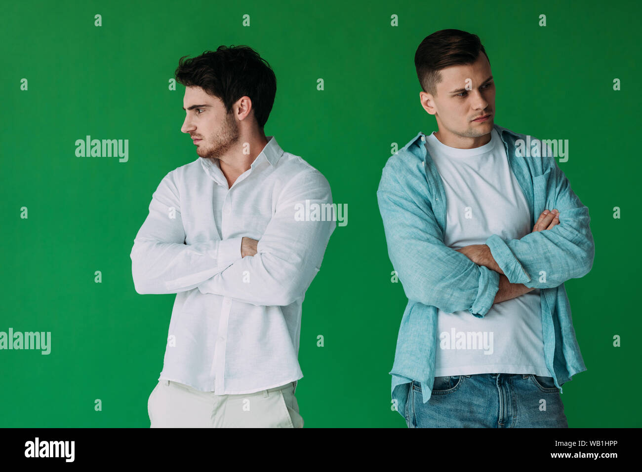 two offended men in shirts standing with crossed arms isolated on green ...