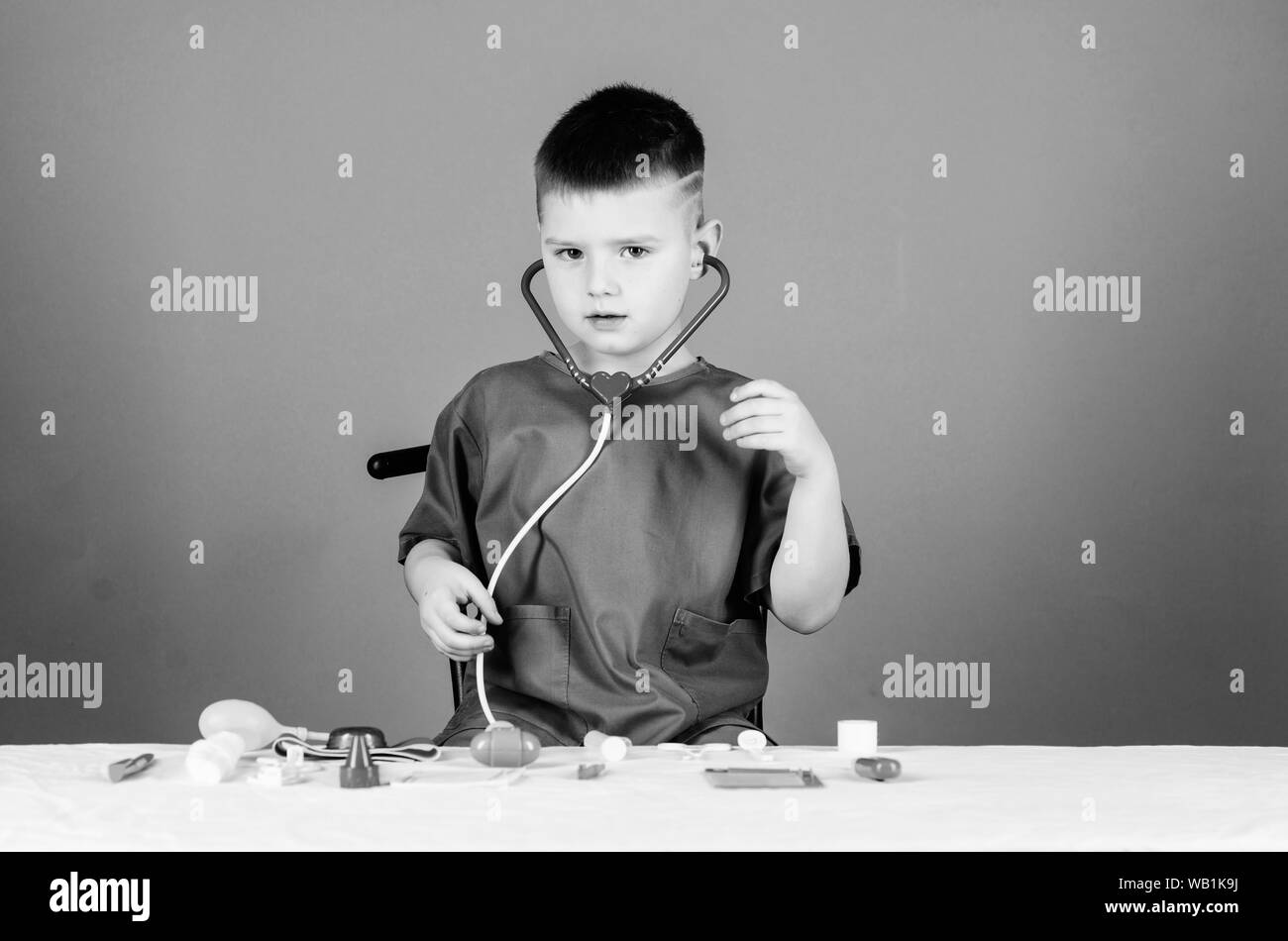 Kid little doctor sit table with stethoscope and medical tools ...