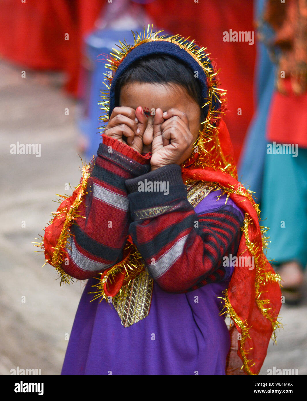 Girl child beggar shy in front of the camera in colorful religious ...