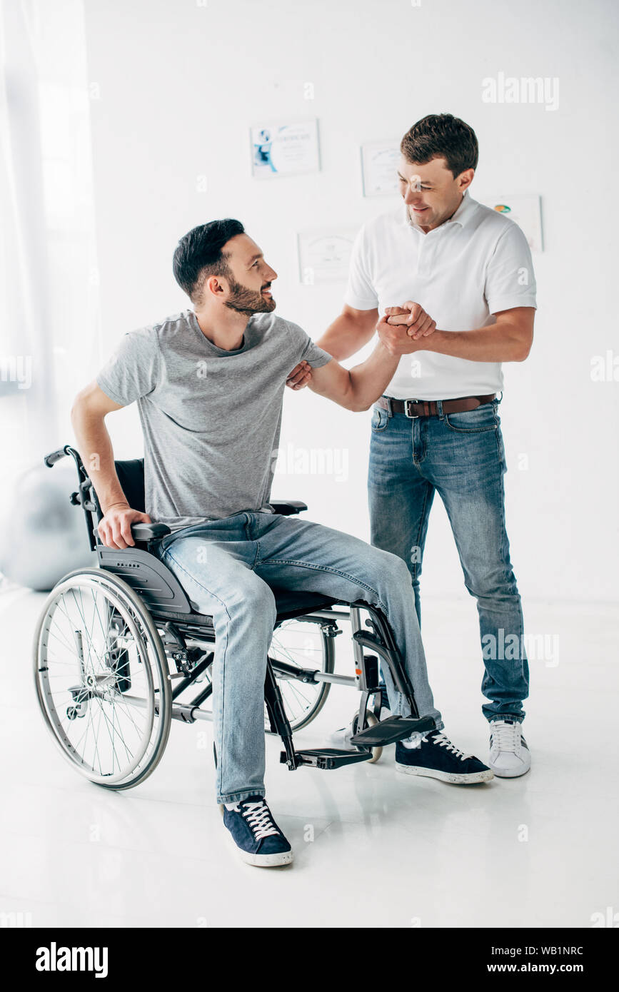 Physiotherapist helping handicapped man in Wheelchair during recovery ...