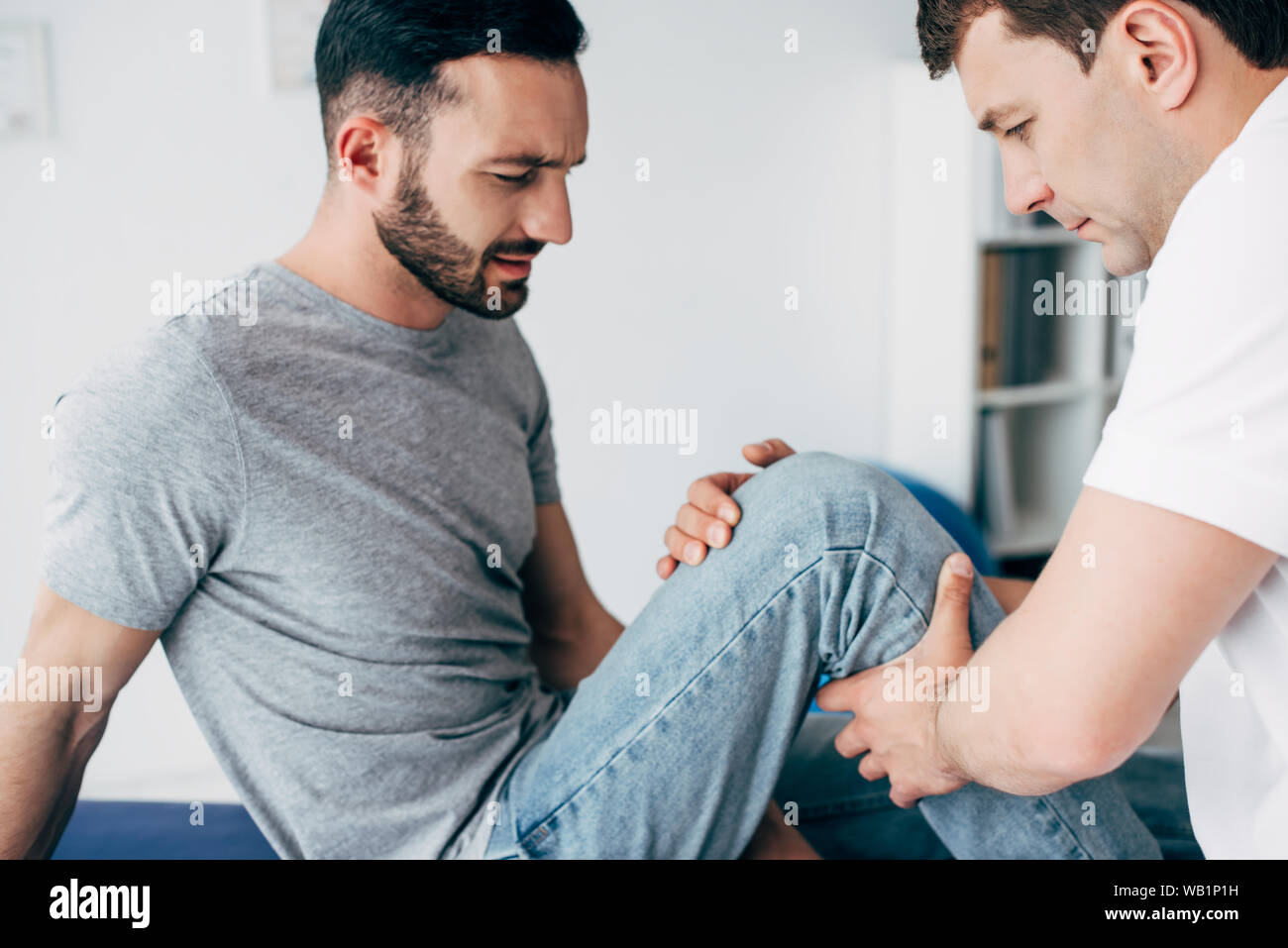 handsome Physiotherapist massaging leg of good-looking patient in ...