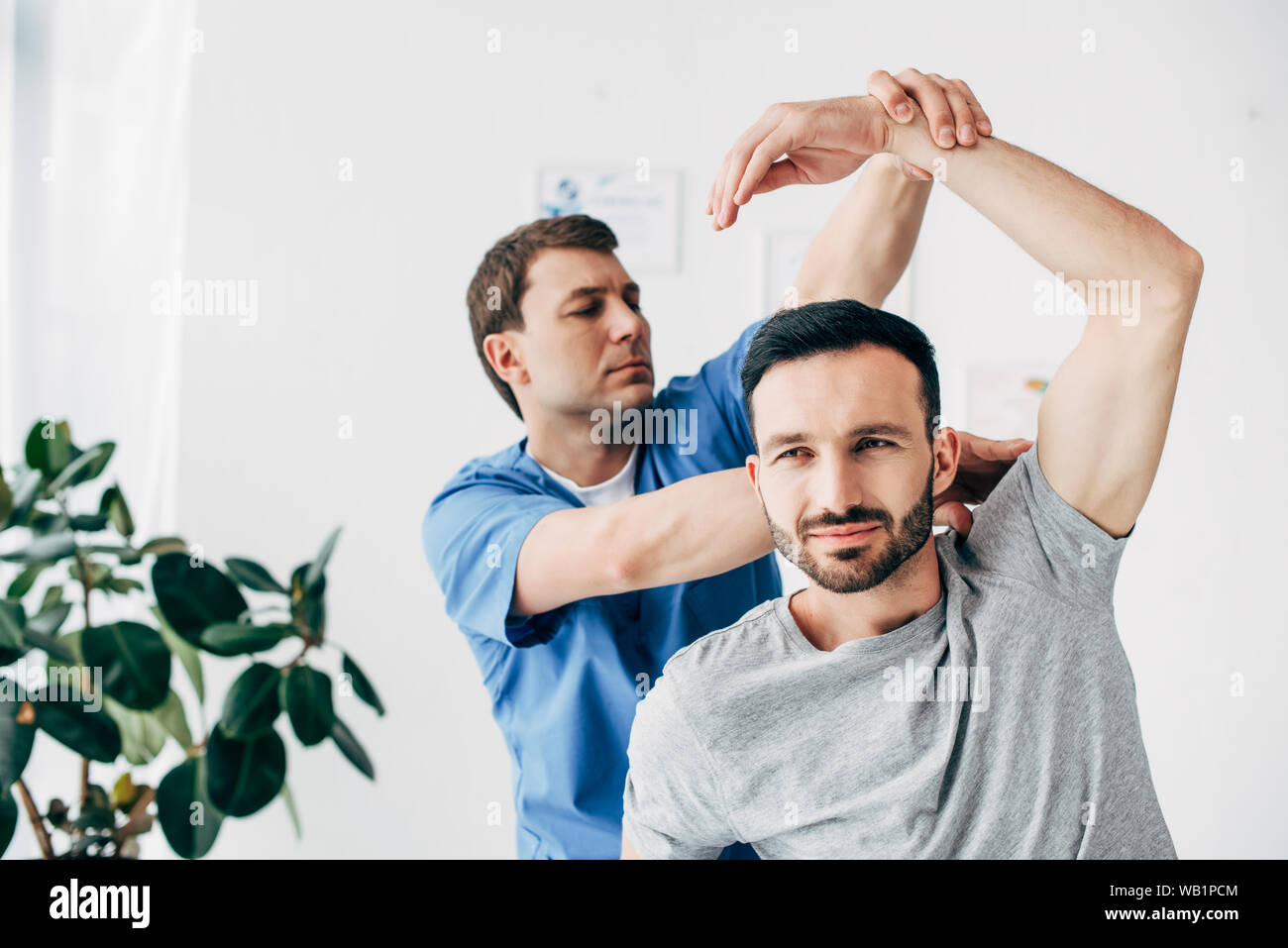 chiropractor stretching arm of handsome patient in hospital Stock Photo ...