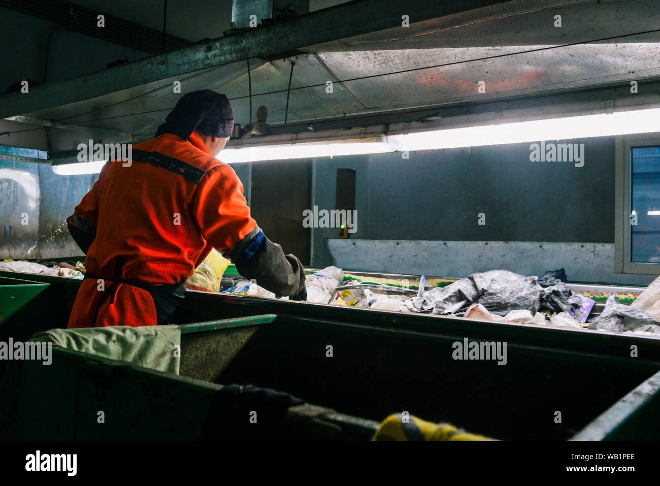 Worker at a waste processing plant. A man sorts rubbish with his hands ...