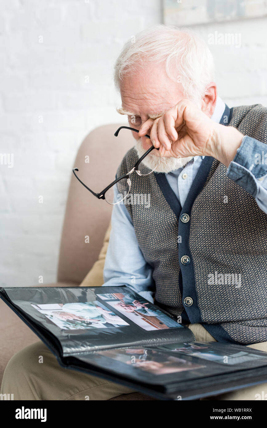Upset grey haired man crying, and holding photo album in hands Stock ...