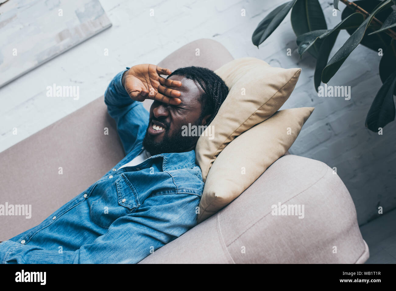exhausted african american man lying on sofa and suffering from ...