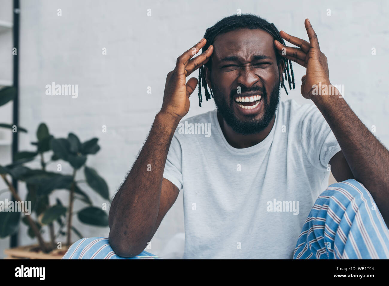 screaming african american man suffering from headache in bedroom Stock ...