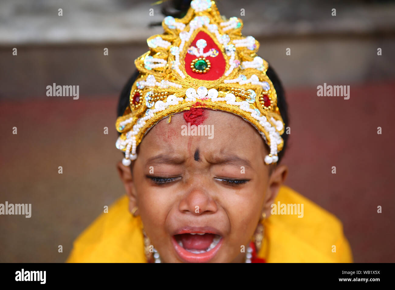 A child dressed as lord Krishna cries during the Celebration ...