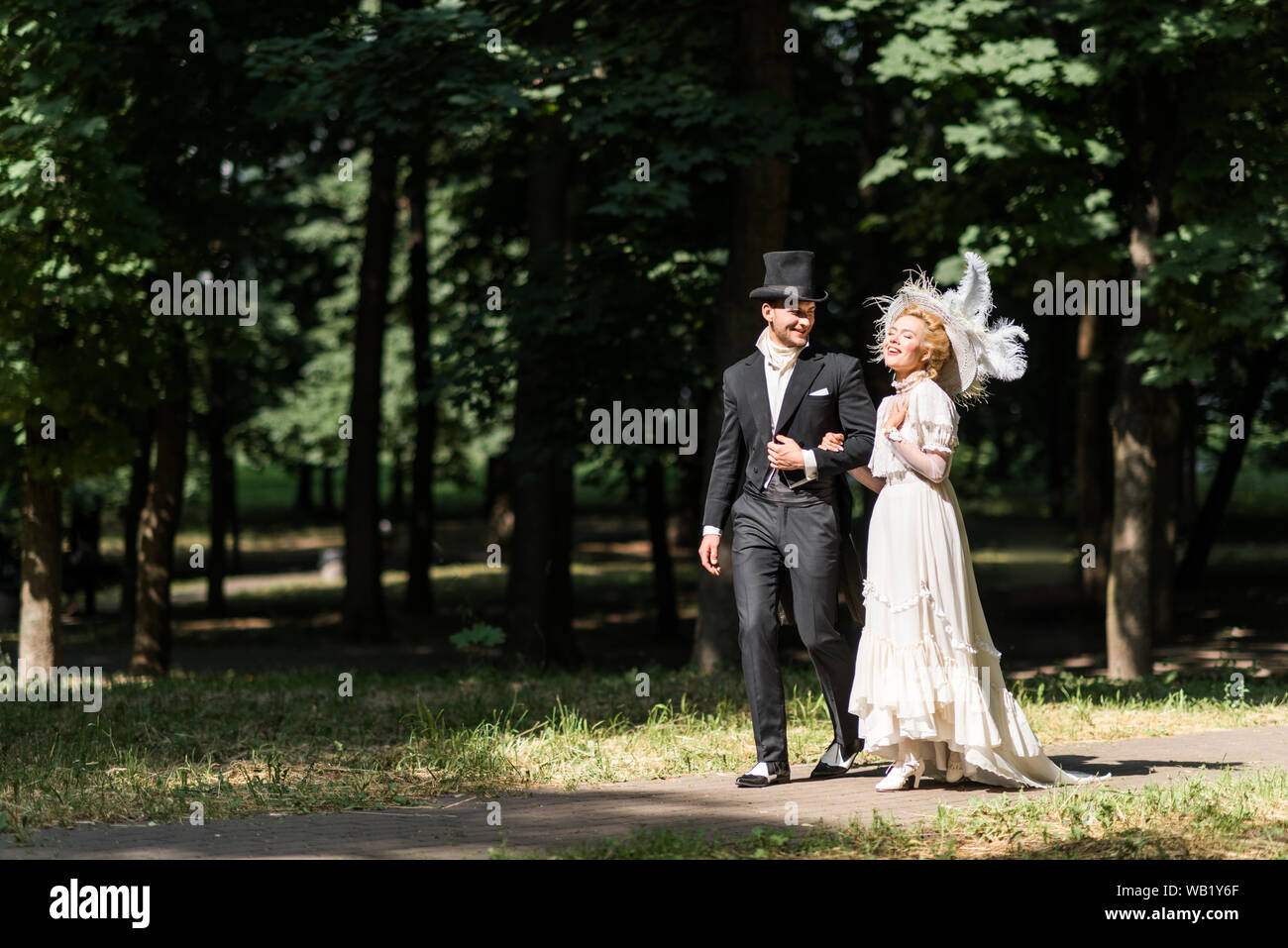 happy young victorian woman and handsome man in hat walking outside ...