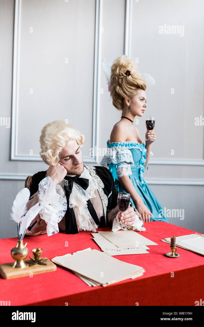 sad victorian man in wig holding glass wine near pompous woman Stock ...