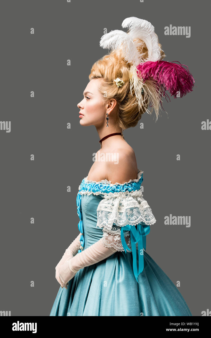 side view of elegant victorian woman in wig and blue dress isolated on ...